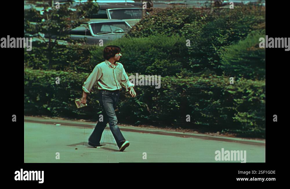 1970s: Man walks down a sidewalk. Man hangs up a telephone and pulls ...