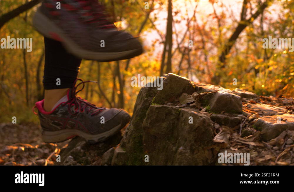 LENS FLARE: Hiker steps on rock while exploring trails on a sunny fall ...
