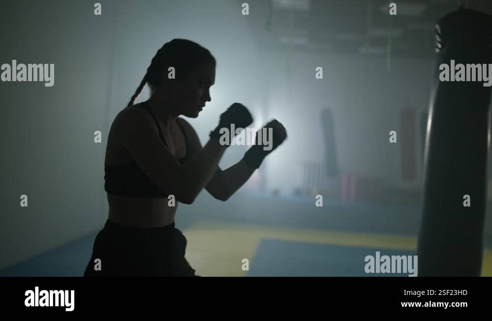 Female fighter trains his punches and defense in the boxing gym ...