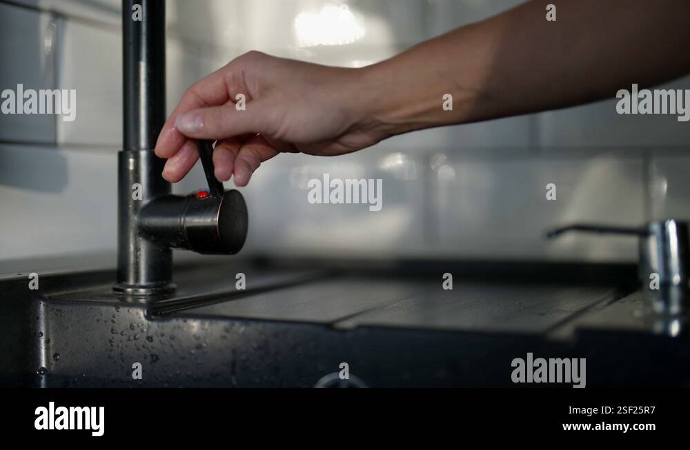 woman is opening tap with water in kitchen, slow motion shot, closeup ...