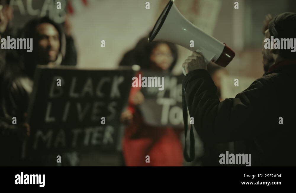 Young man with megaphone shouting slogans and raising clenched fist up ...