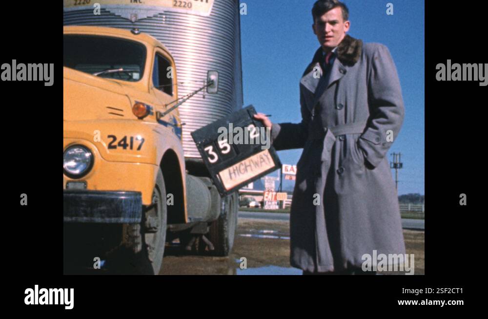 1950s: Man holds clapboard near truck. Cargo truck pulls into parking ...