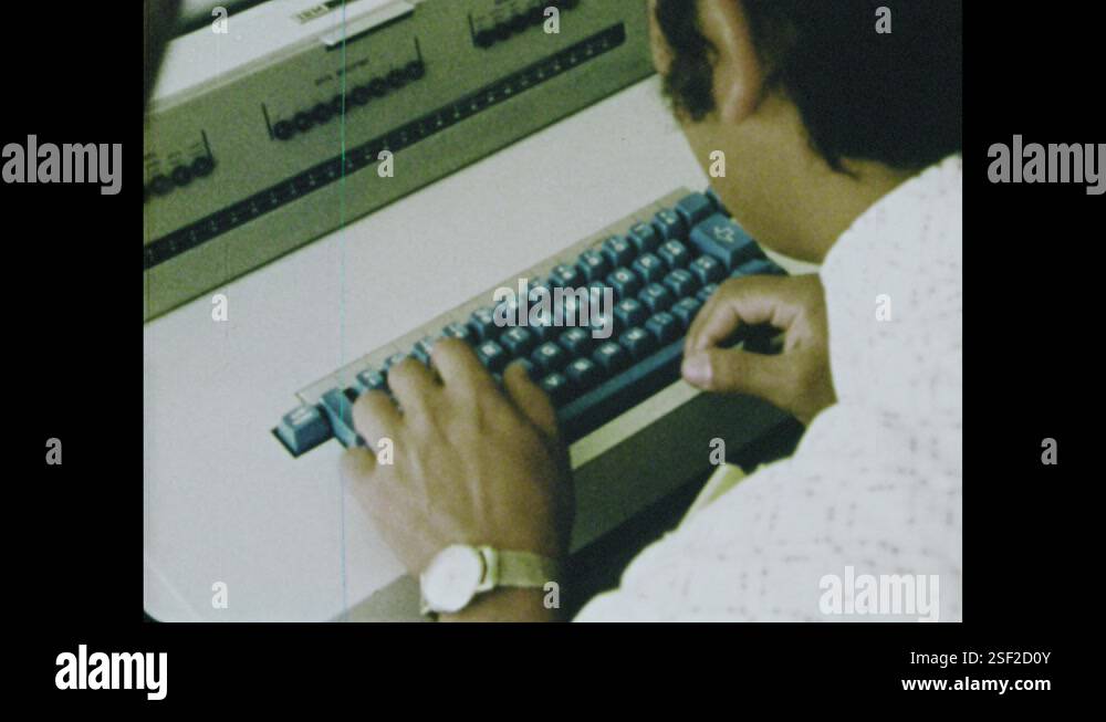1970s: Man pressing buttons on computer console. Hands typing at ...
