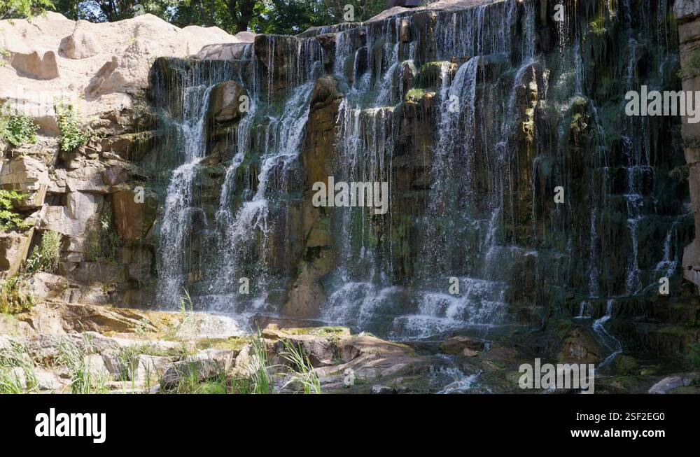 Magic waterfall streaming down a sheer stone wall on a sunny day in ...