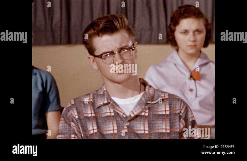 1950s: Slate. Boy in classroom sits shaking his head. Slate. Boy reads ...