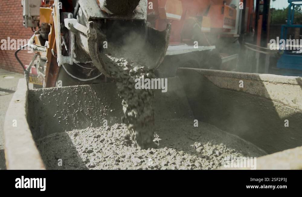 A concrete mixer pouring concrete into a dumper on a dusty summer's day ...