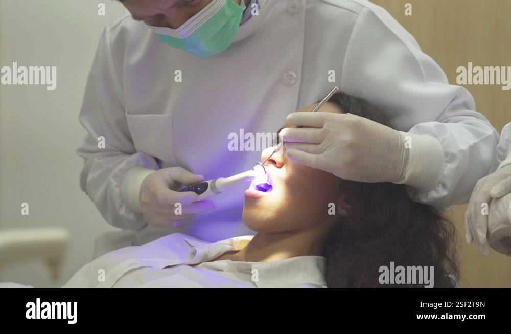 A dentist checking up Latin woman's teeth by using dental mouth mirror ...