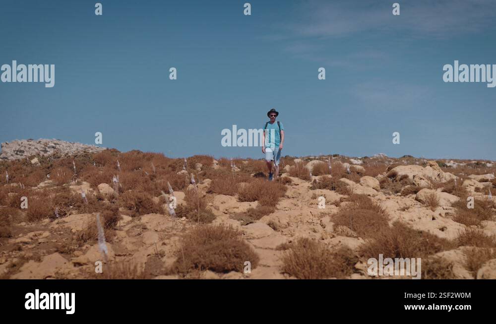 A man walks through the hills with bushes. Summer and heat in the ...
