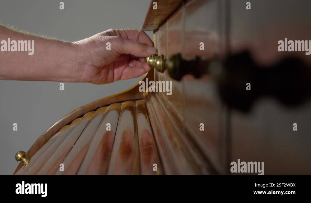 Man's hand taking an item from a small drawer in an ornate wooden desk ...