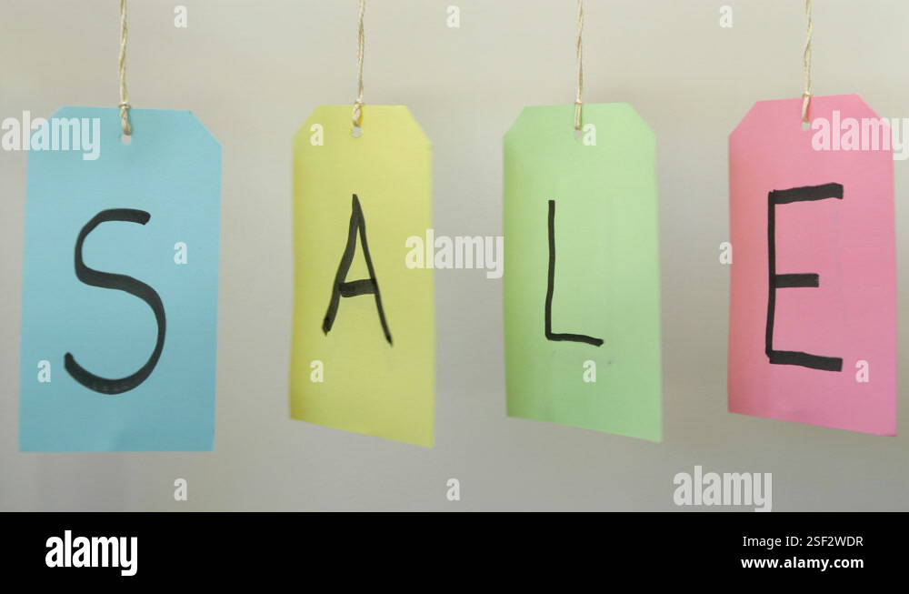 Hanging tags / labels twirling around by attached string, spelling SALE ...