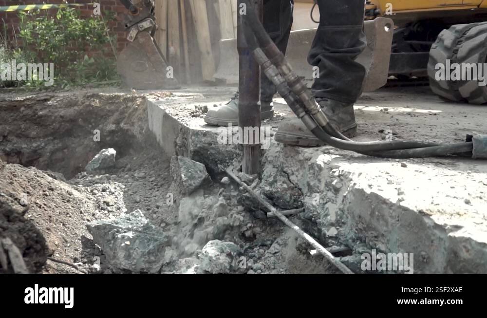 Construction worker breaking concrete using a hydraulic concrete ...