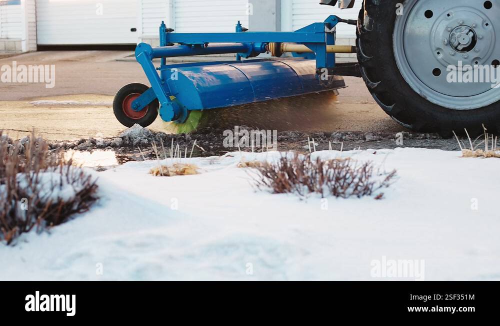 The tractor sweeps the area from dirt and snow with a brush ...