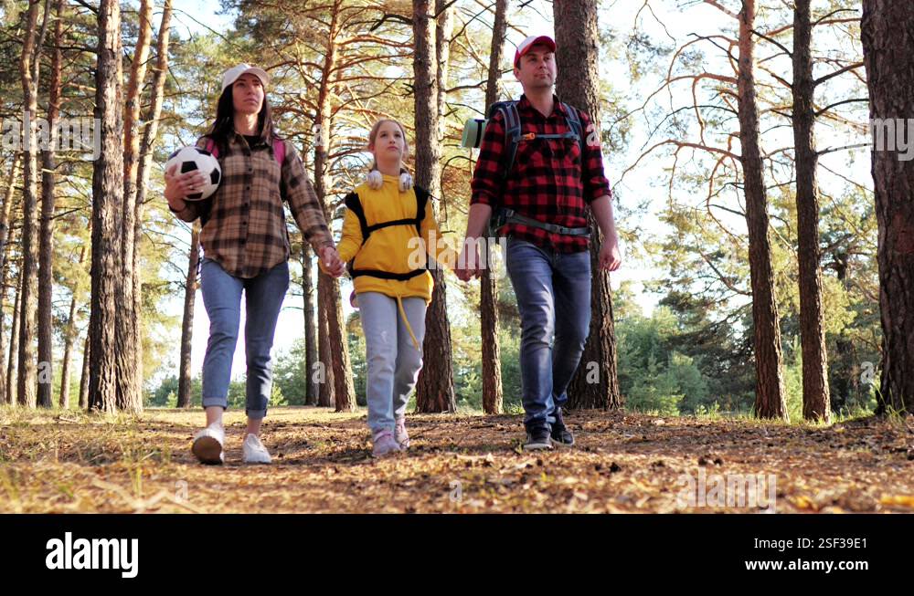 Happy family hiking through a forest. Parents with daughter walking by hiking Stock Video ...