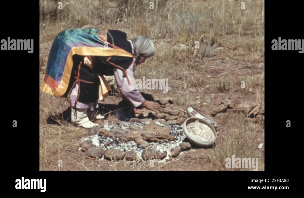 1940s: Native American woman builds stone kiln around clay pot. Fire ...