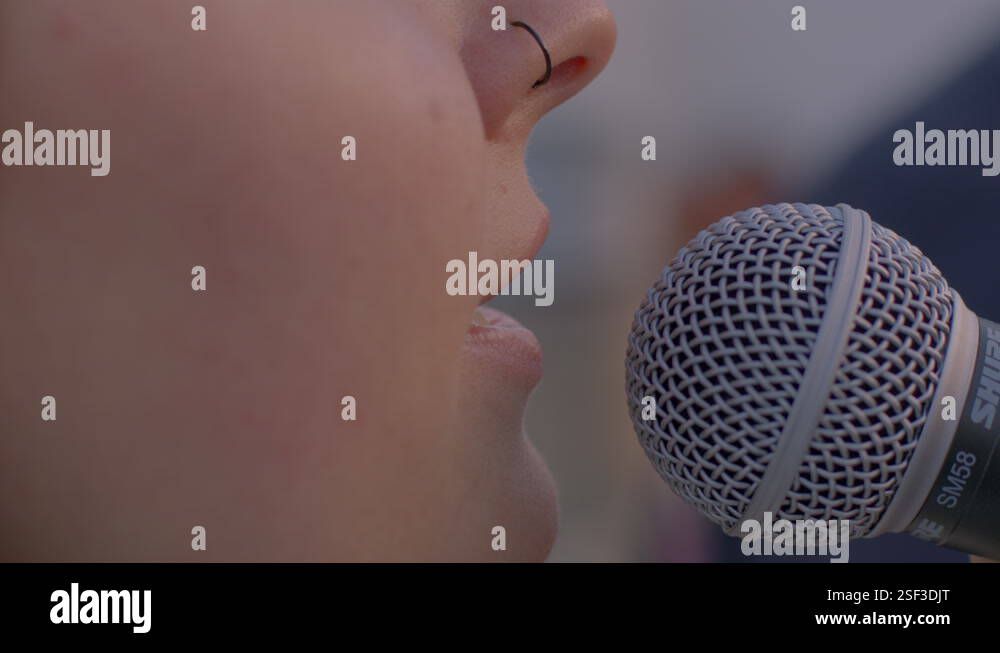 Close-up of the mouth of a girl singing into a microphone. The female ...