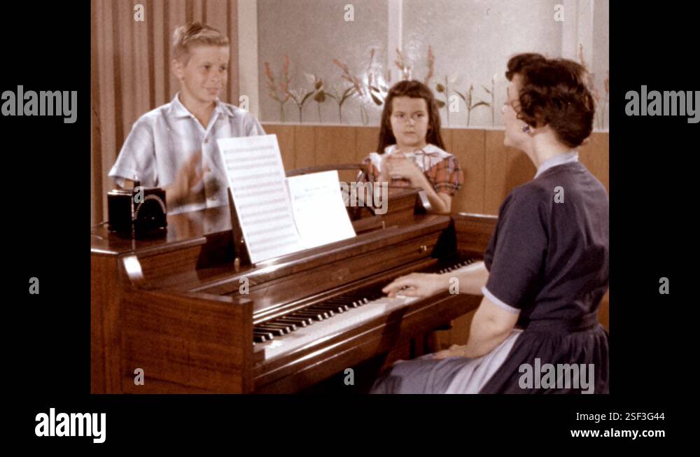 1950s: Woman at piano with boy and girl, woman playing, boy and girl ...