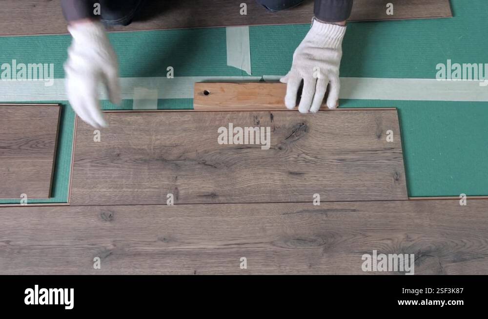 A worker hands knocking on a laminate connecting the panels with a Lock ...