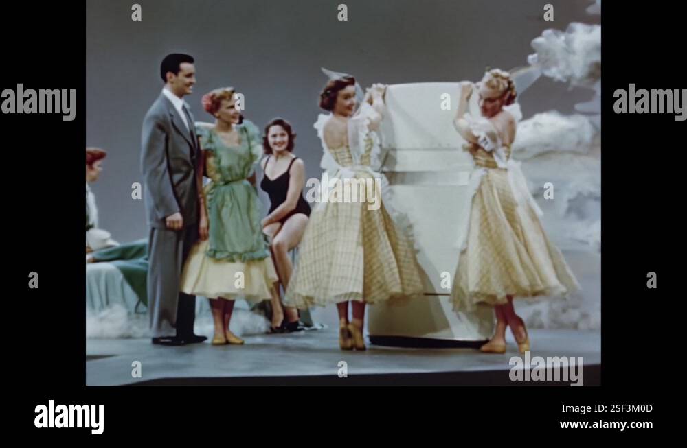 1950s: Man and women dance around refrigerator. Women dance down ramp ...