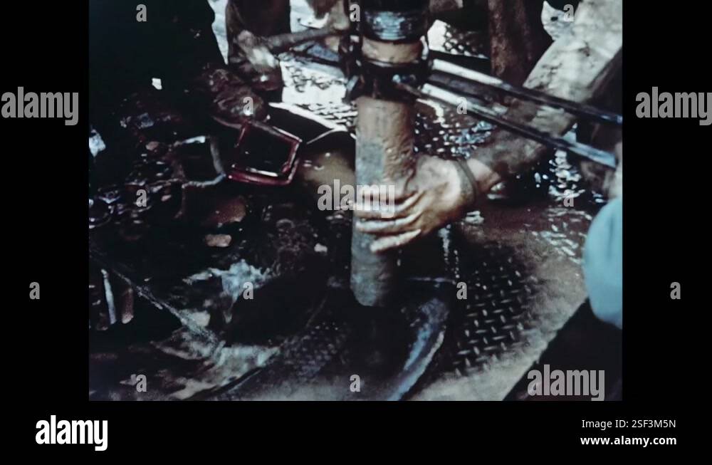 1950s: Men remove core sample of strata from oil drilling pipe. Truck ...