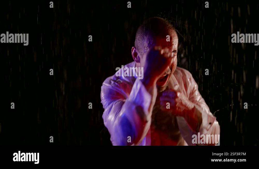 mad furious man is fighting with camera, punching by arms in rain Stock ...