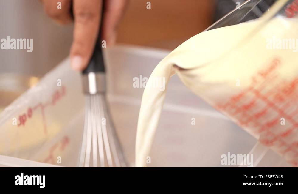 Pour milk into the dry ingredients to make waffle batter and mixing it ...