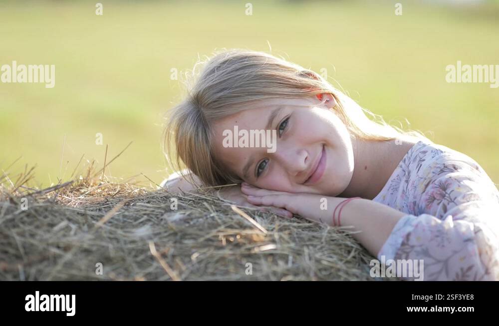 Life in the countryside. Portrait of a smiling blonde girl lying on a ...