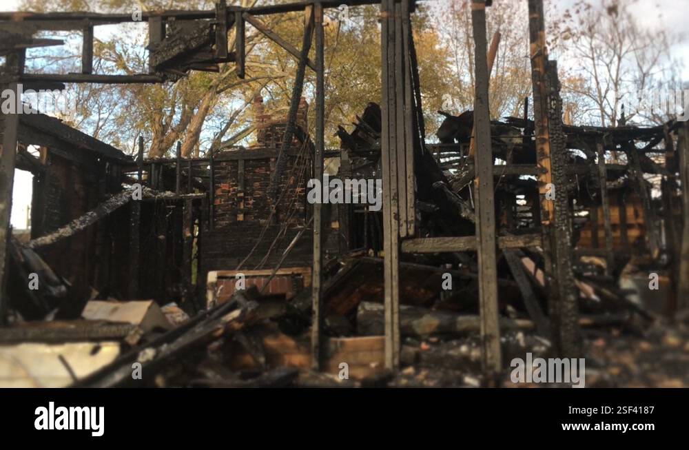 Rubble and brick fireplace from a charred home destroyed by fire. Blue ...