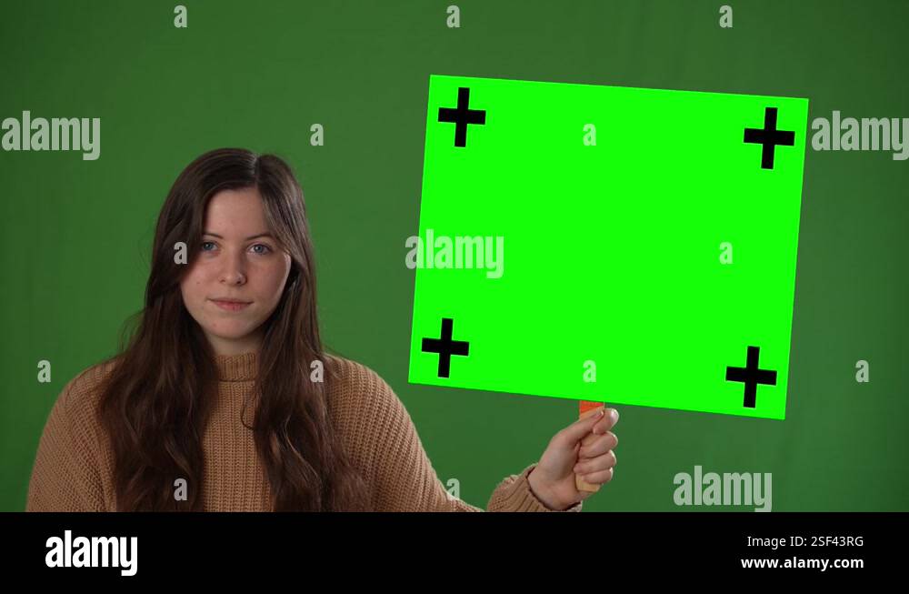 A serious woman holds a green screen chroma key blank protest sign on ...