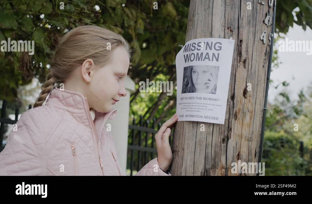 A sad, crying child stands at an ad for a missing woman Stock Video ...