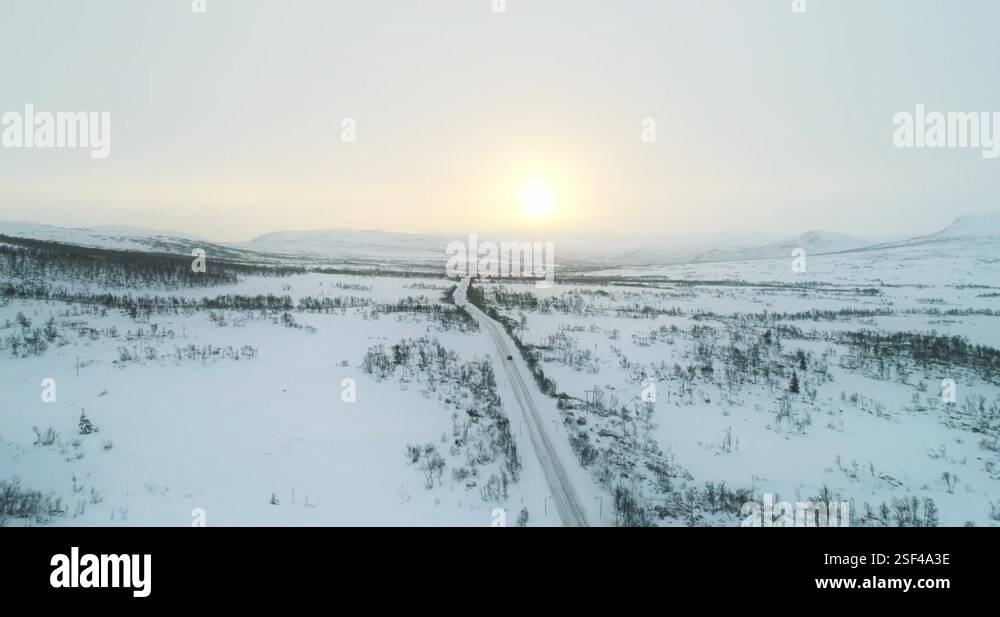 Car driving on Arctic winter road towards soft light sunset above ...