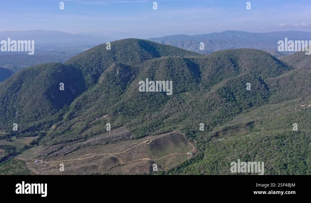 Aerial forward flight over green mountain formation during foggy day on ...