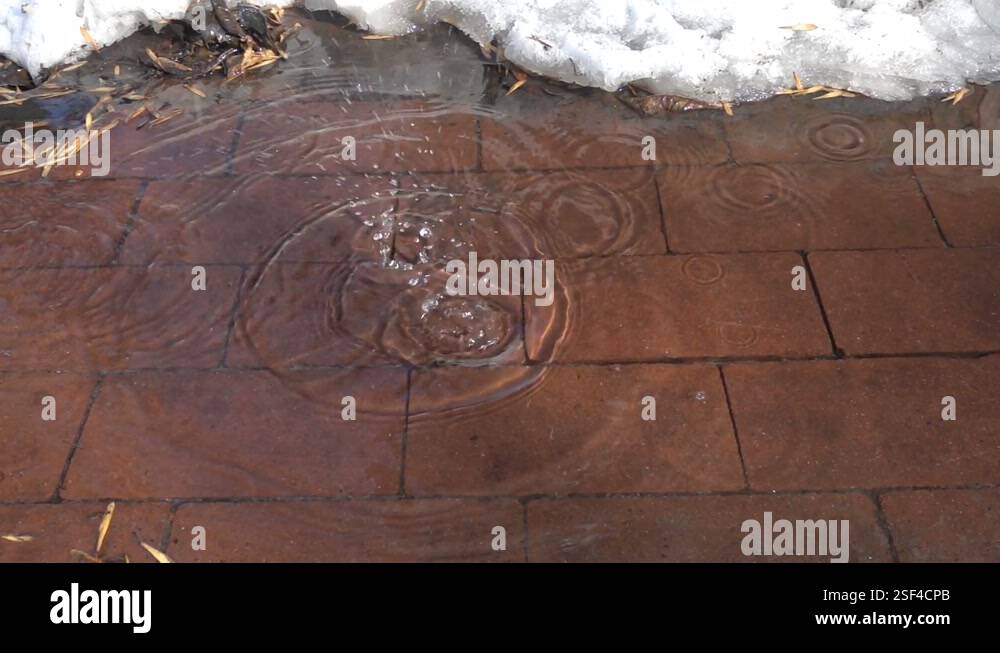 Water drops fall in slow motion into a puddle and snow Stock Video ...