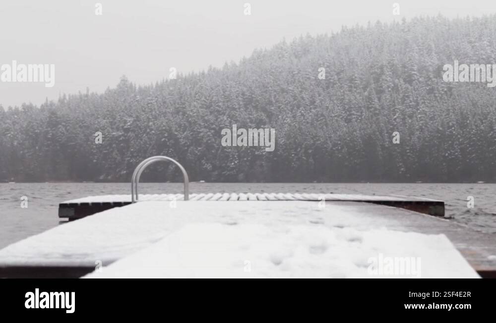 Snow falling on Alta lake with water rippling and docking deck swaying ...