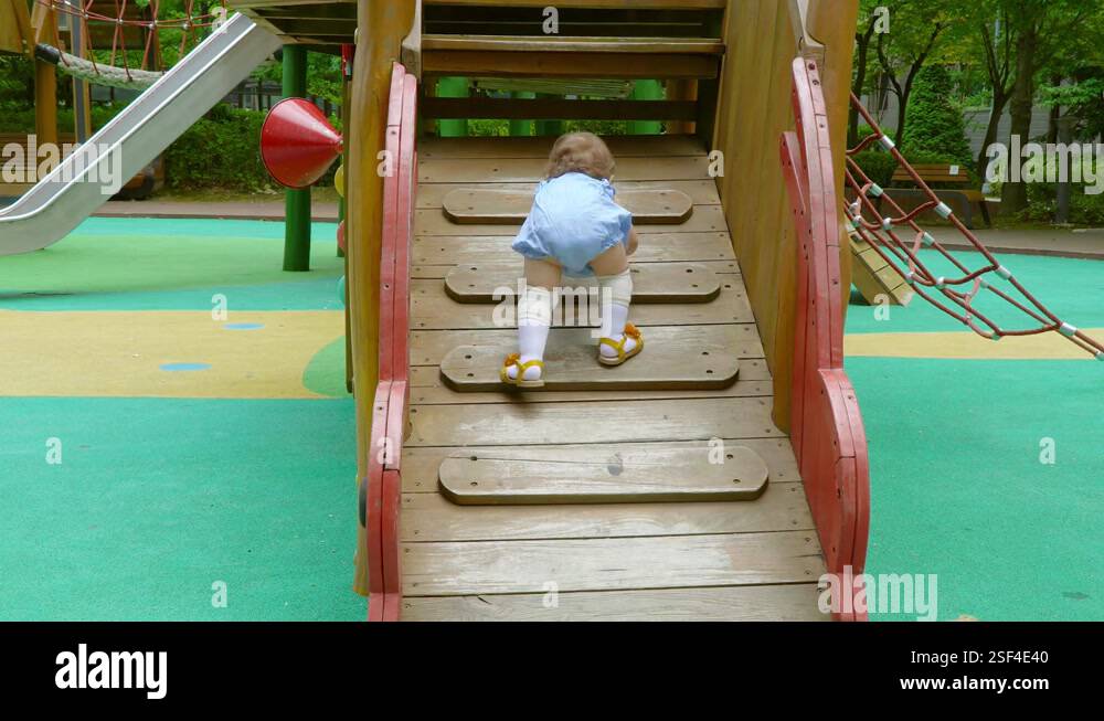 Little baby girl struggling to climb wooden ladder at playground -back ...