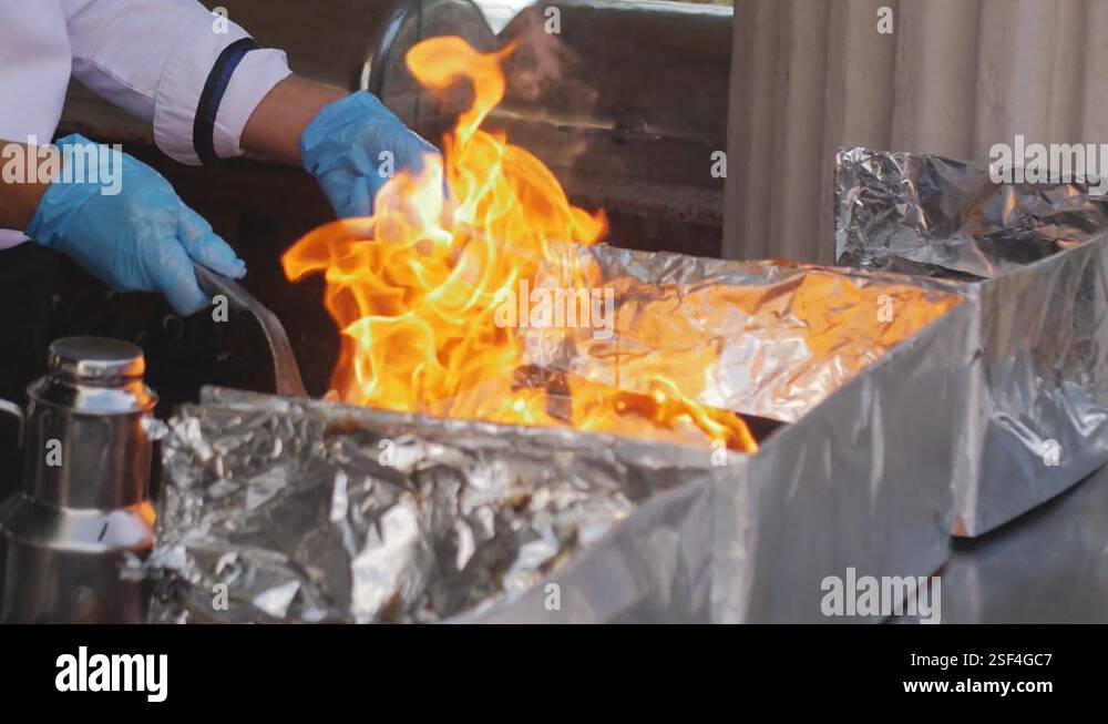 A close-up of a restaurant chef cooking on fire in an outdoor kitchen ...