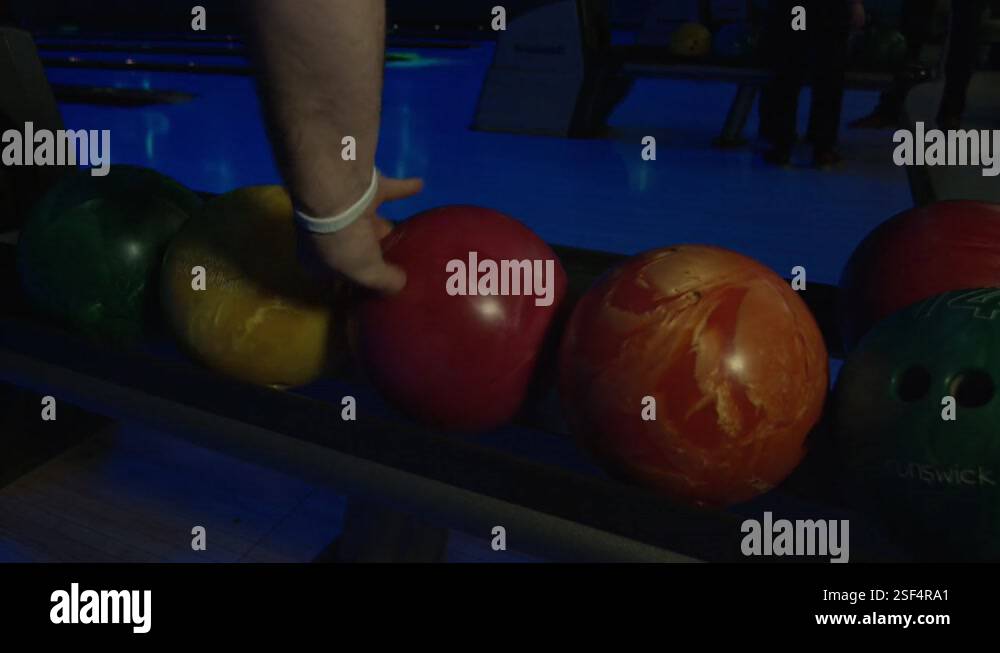 A hand grabbing a red bowling ball out of the ball return or pinsetter ...