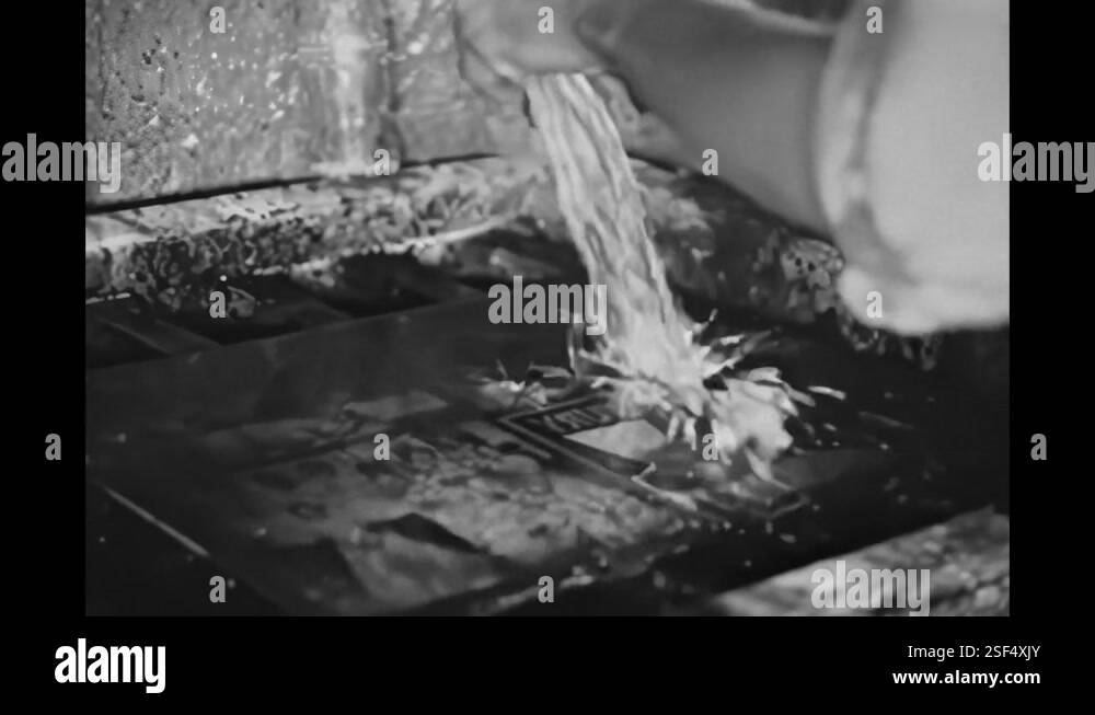 1950s: Man securing photograph into apparatus. Liquid running over ...