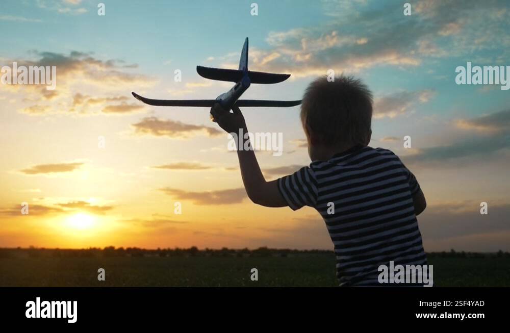 boy kid run in the park across the field play with an toy airplane in ...