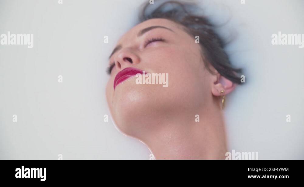 Beauty portrait of young woman face and hair floating in milk bath ...