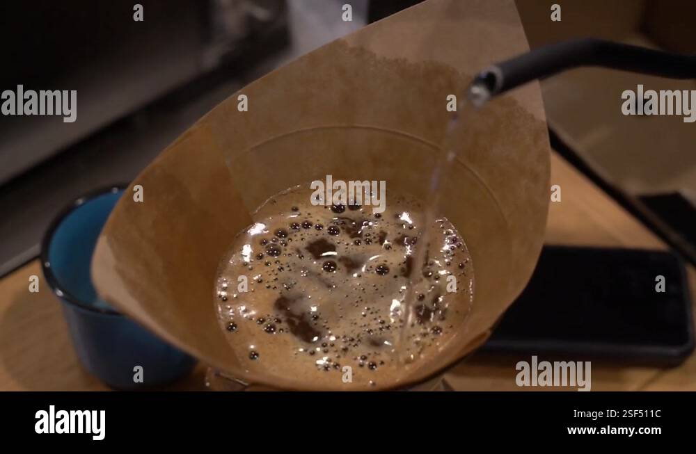 Coffee filter with fresh crushed grains being filled with hot water for ...