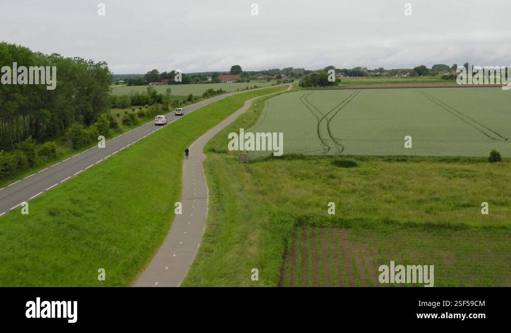 Long aerial tracking shot of traffic through agricultural land on the ...