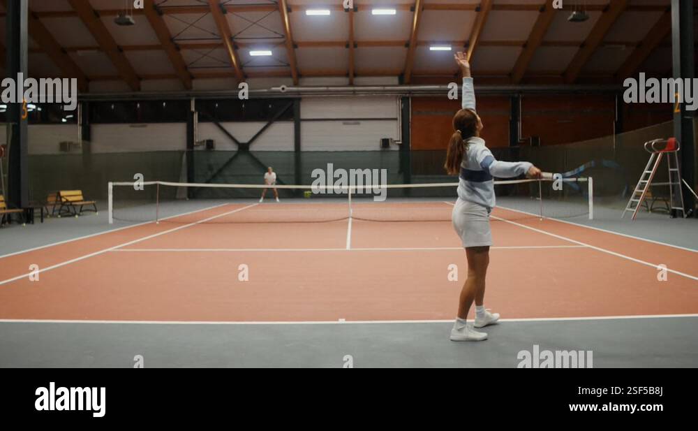 Young athletes play tennis in a large hall alone, throwing the ball ...