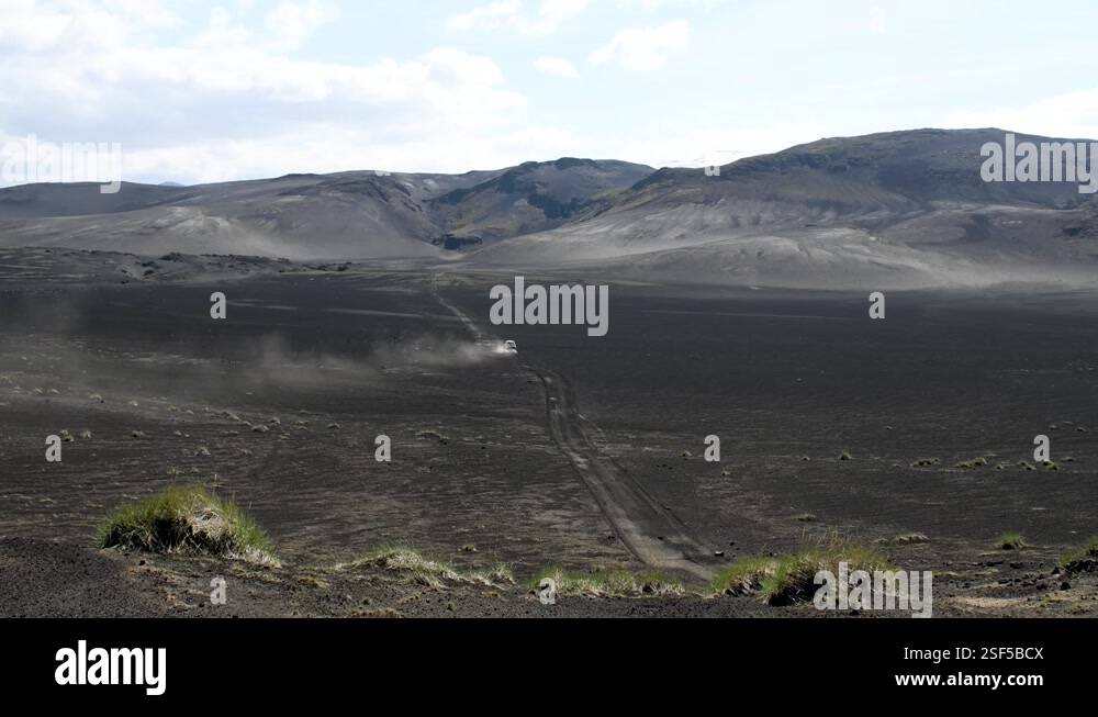 White car driving along desert area in Iceland raising dust in the air ...