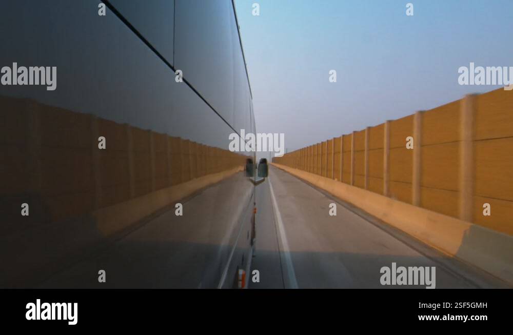 Side view of a public bus, shuttle, or school bus driving and the road ...