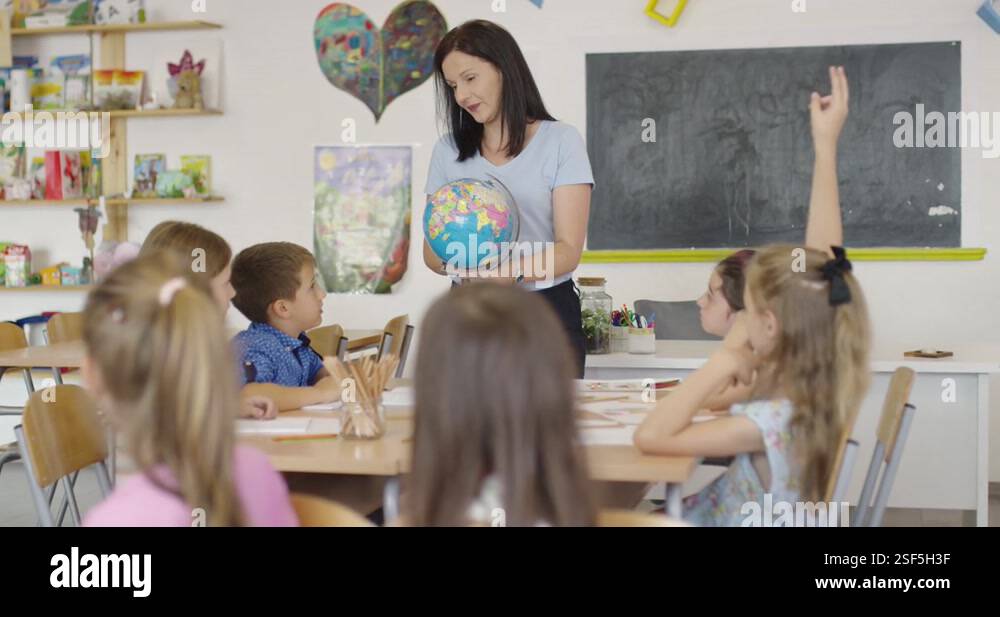 Female teacher with kids in geography class looking at globe. Side view ...