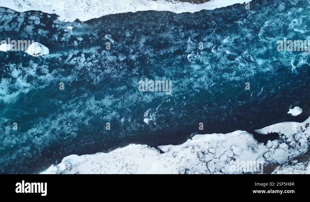Strong streams of cold blue water and melting ice from waterfall ...