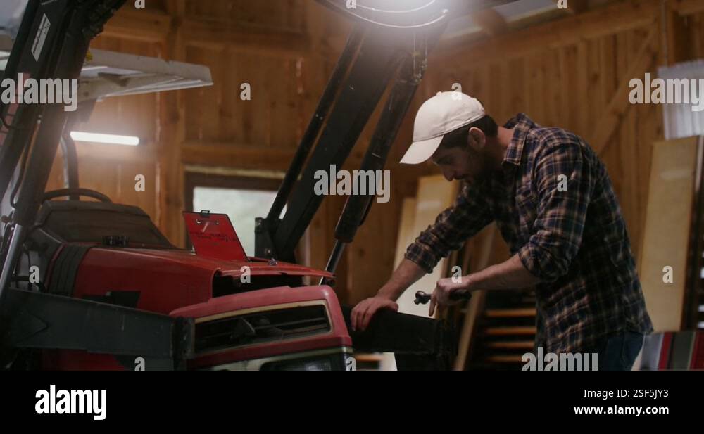 A young man repairs a small agricultural tractor in a wooden barn Stock ...