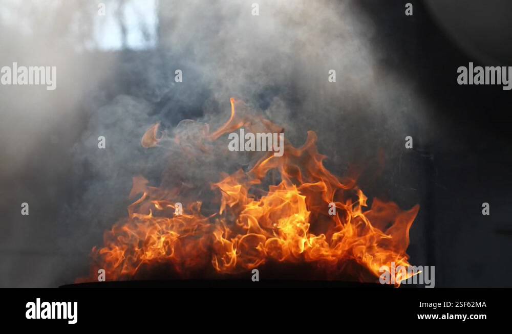 A raging flame of fire in slow motion with rich black smoke. Looks ...