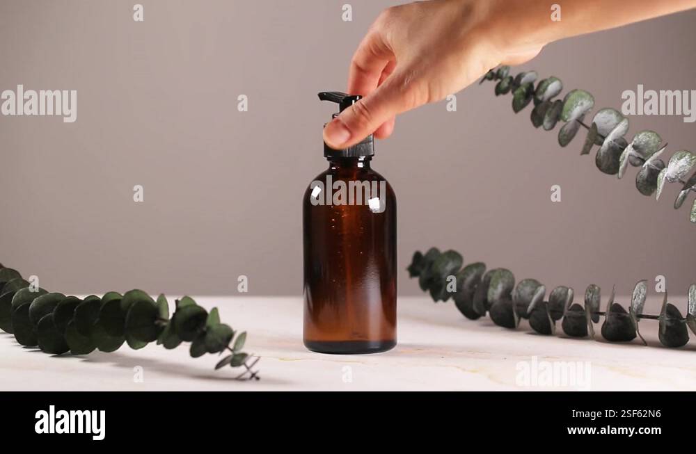 Woman hand refilling shower gel into a reusable glass bottle in zero ...