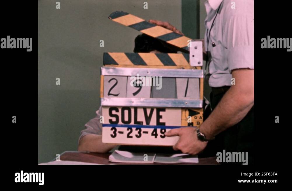 1940s: man sitting at desk talking then flipping over notebook to show ...